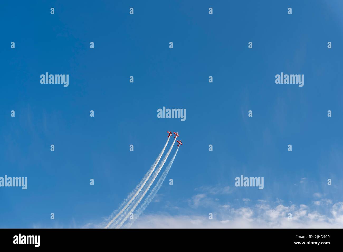 airshow with three red planes flying up and leaving three white stripes ...