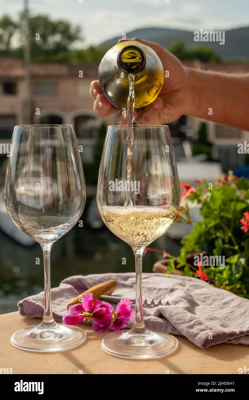 Pouring in glasses of cold white wine in yacht harbour of Port Grimaud ...