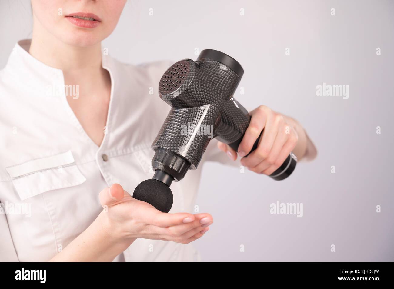 The masseur doctor holds a masseur gun on a white background Stock ...