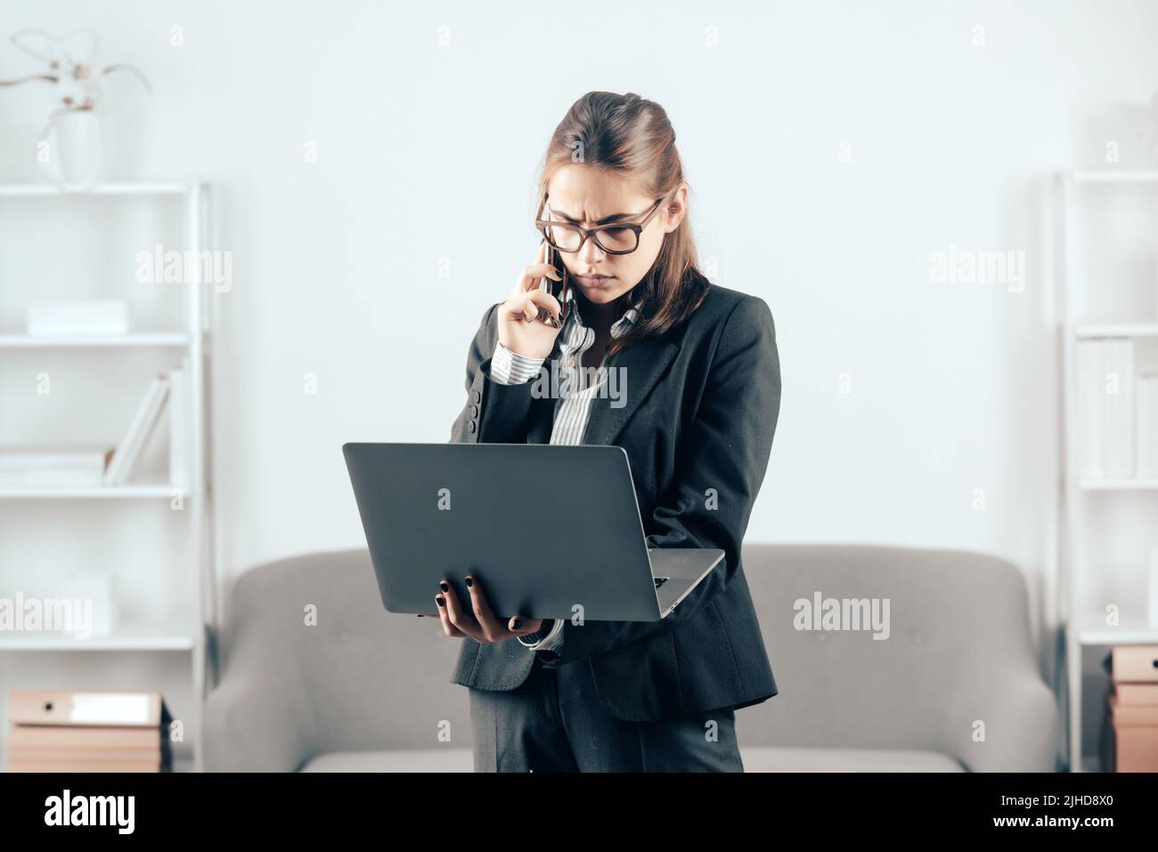 Serious young businesswoman working on laptop with too much work in ...