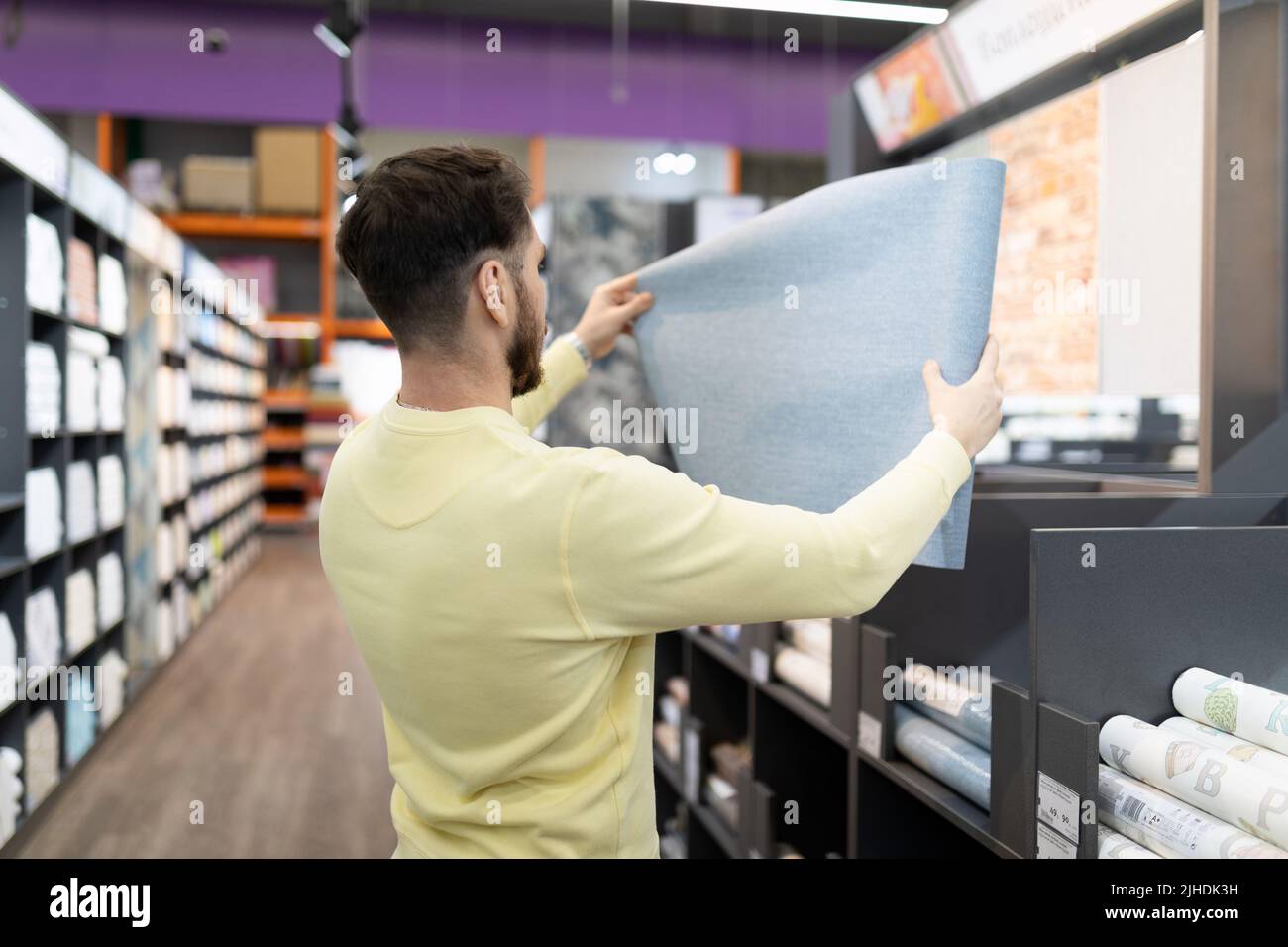 a man chooses wallpaper for pasting walls in a hardware store Stock ...