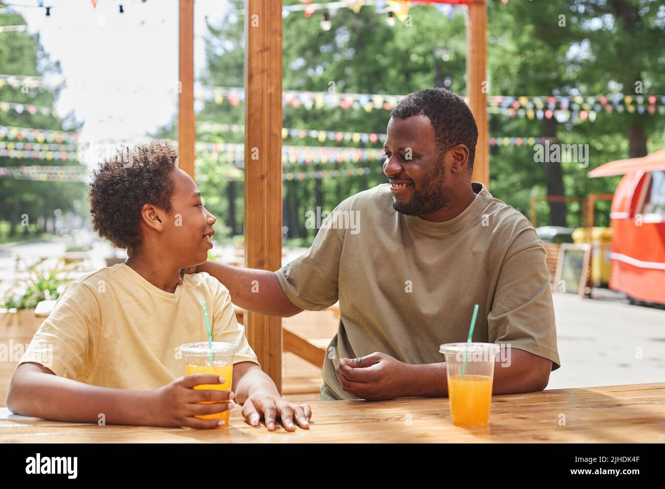 Happy dad talking and laughing with his son while they drinking cold ...