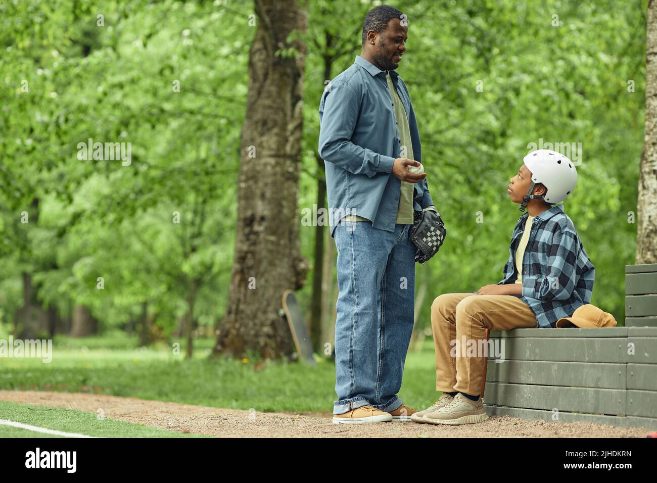 African dad talking to his son before training in baseball in the park ...
