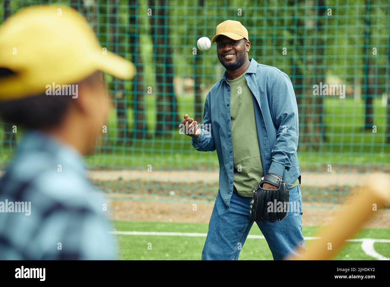 African happy father throwing ball to his son during their baseball ...