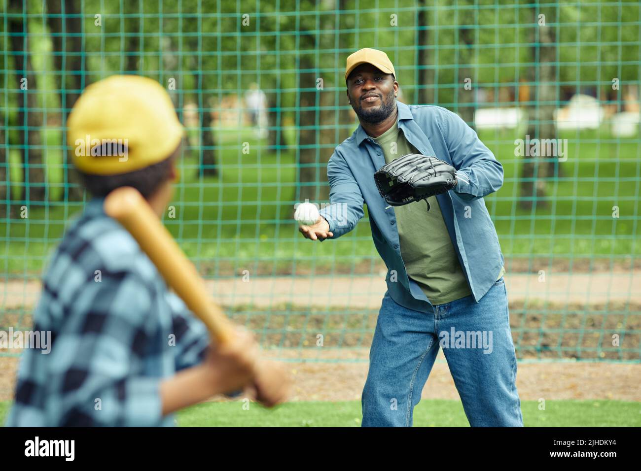 African man catching ball with glove throwing by his son during ...