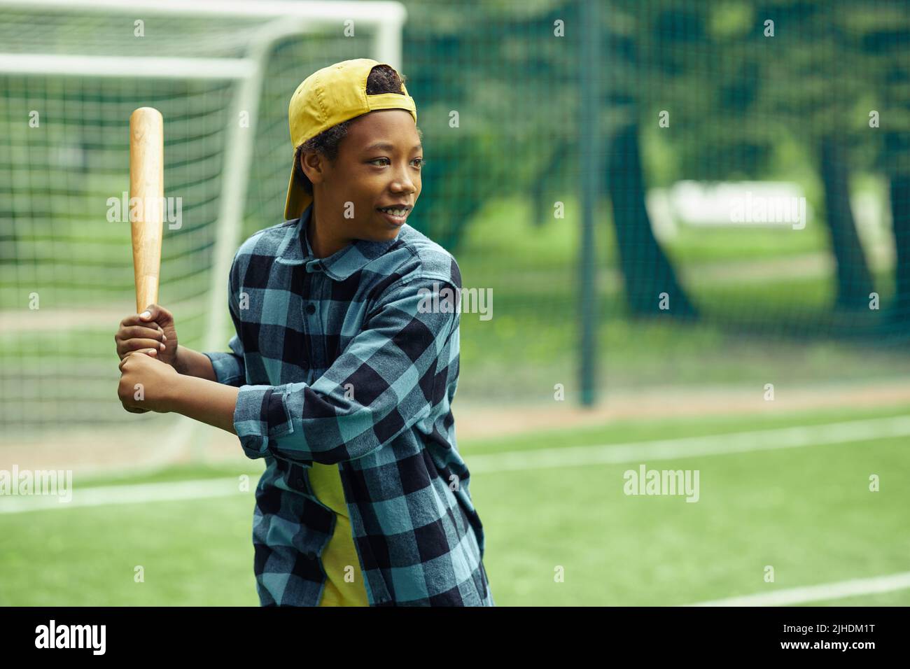 African boy in cap standing with bat and ready to hit the ball during ...
