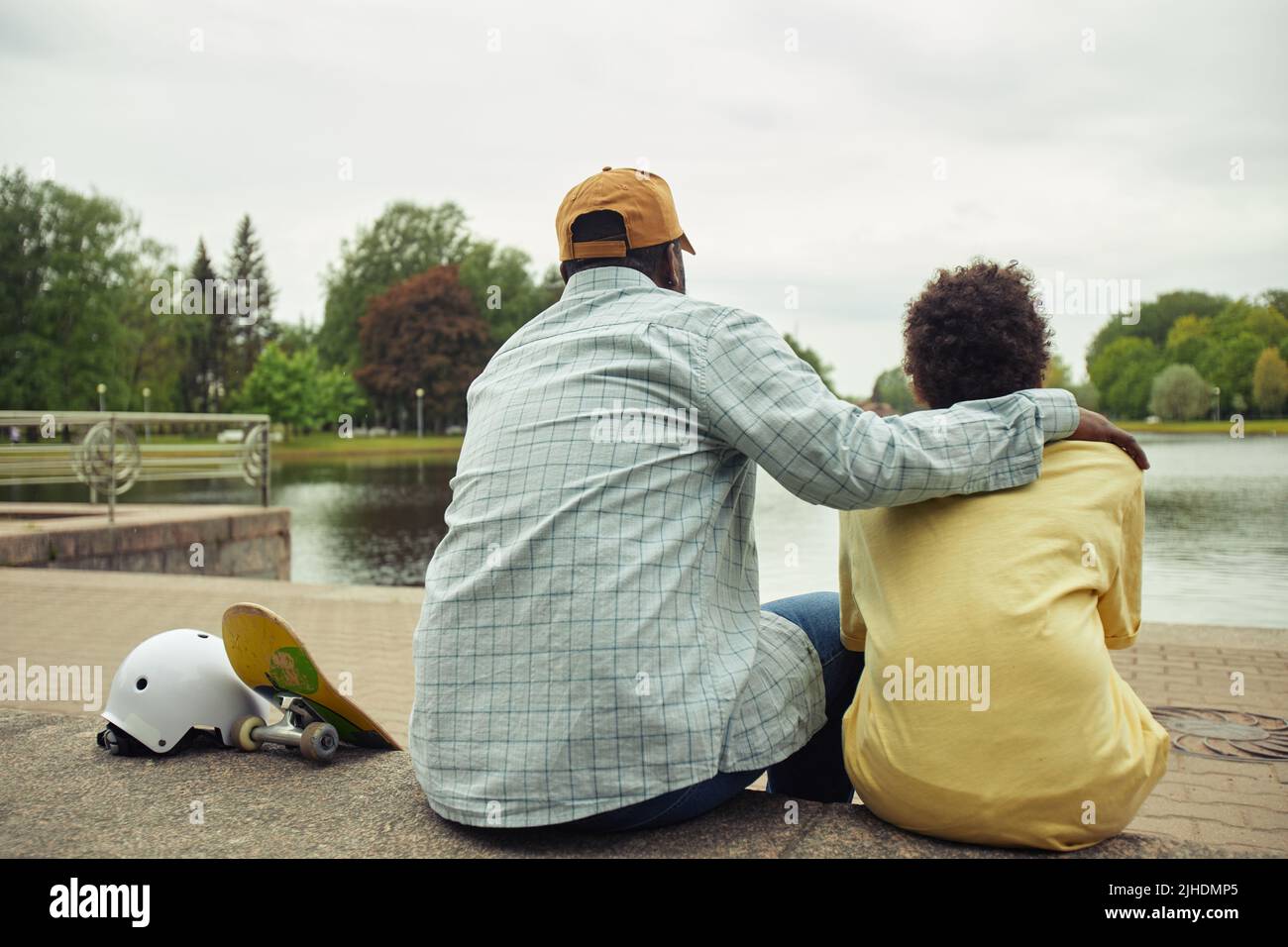 Rear view of dad embracing his son and they resting together after ...