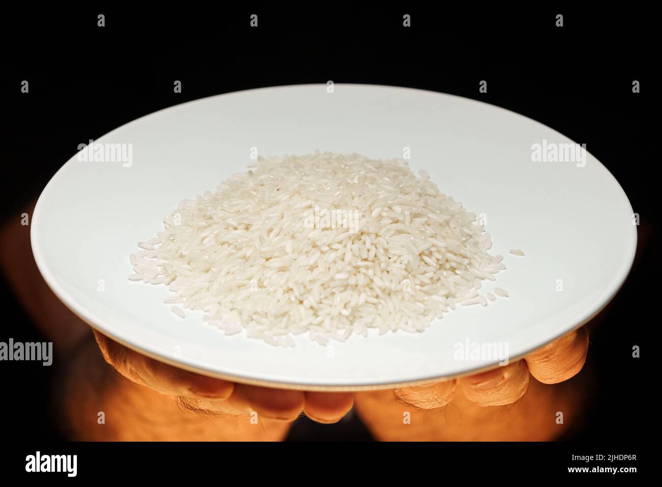 Hands holding a heap of dry rice grain on black background Stock Photo ...