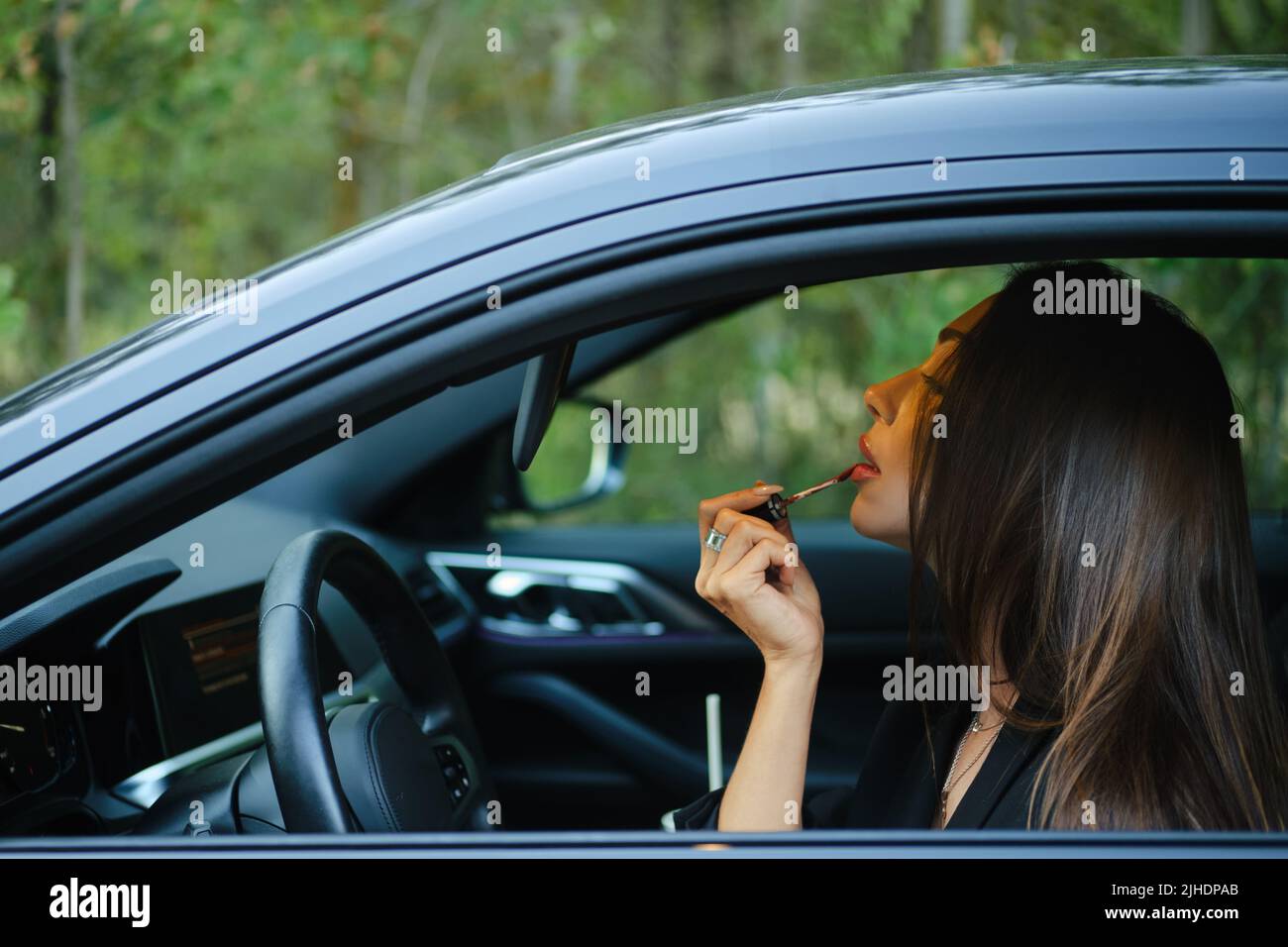 Concentrated woman applying lipstick while sitting in the car Stock ...