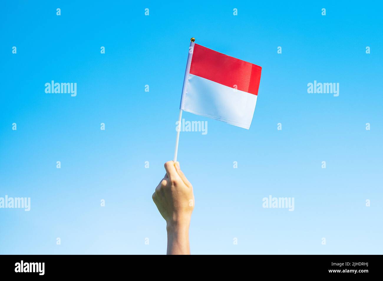 hand holding Indonesia flag on blue sky background. Indonesia independence day, National holiday ...