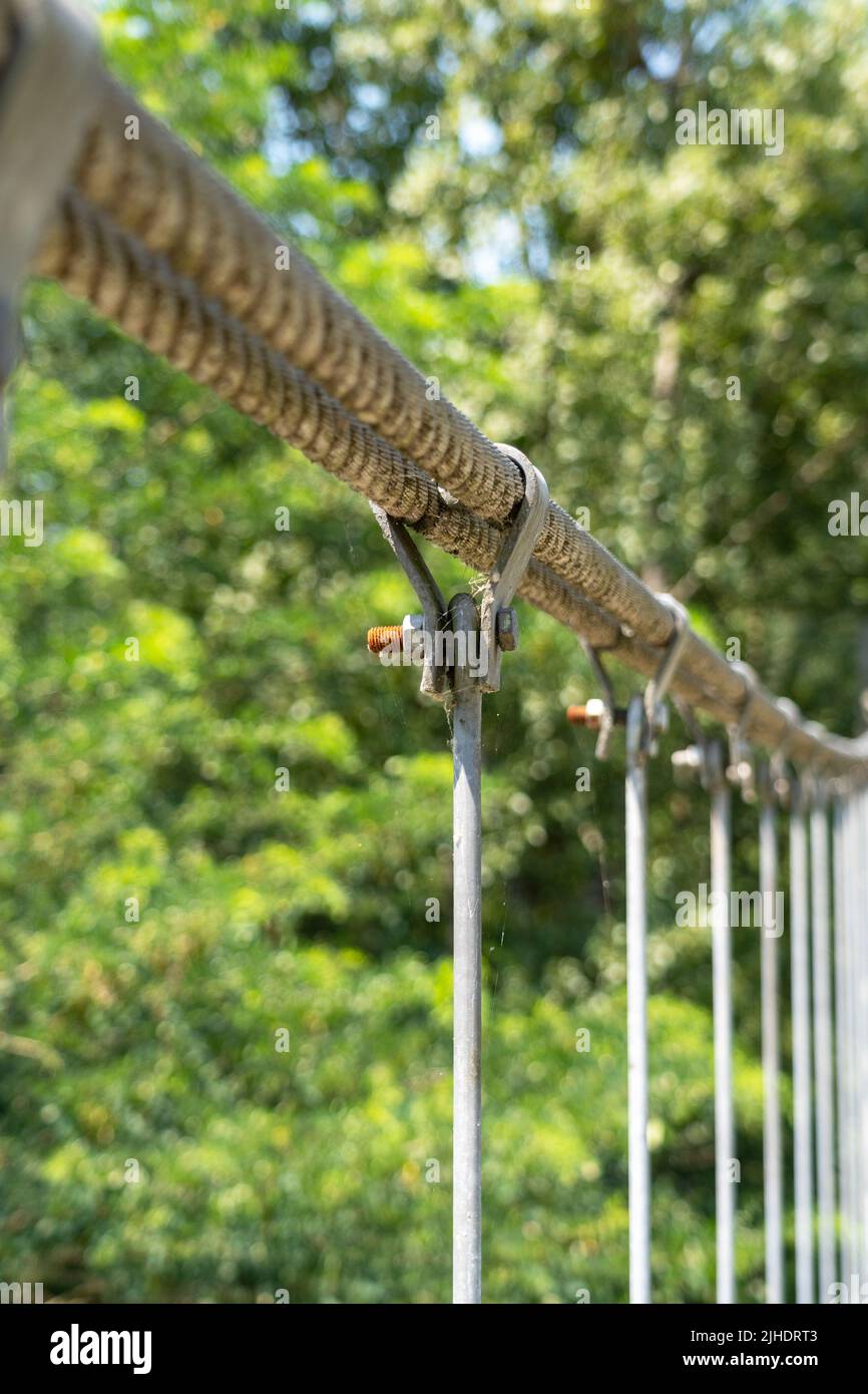 Bolt with nut fastening a suspension bridge to a steel rope close-up ...