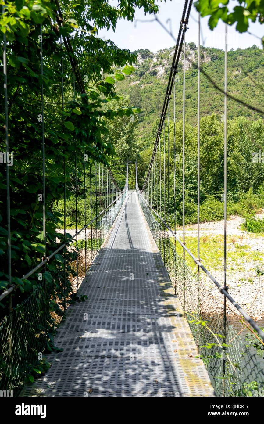 Picturesque metal suspension cable bridge over the river in the ...