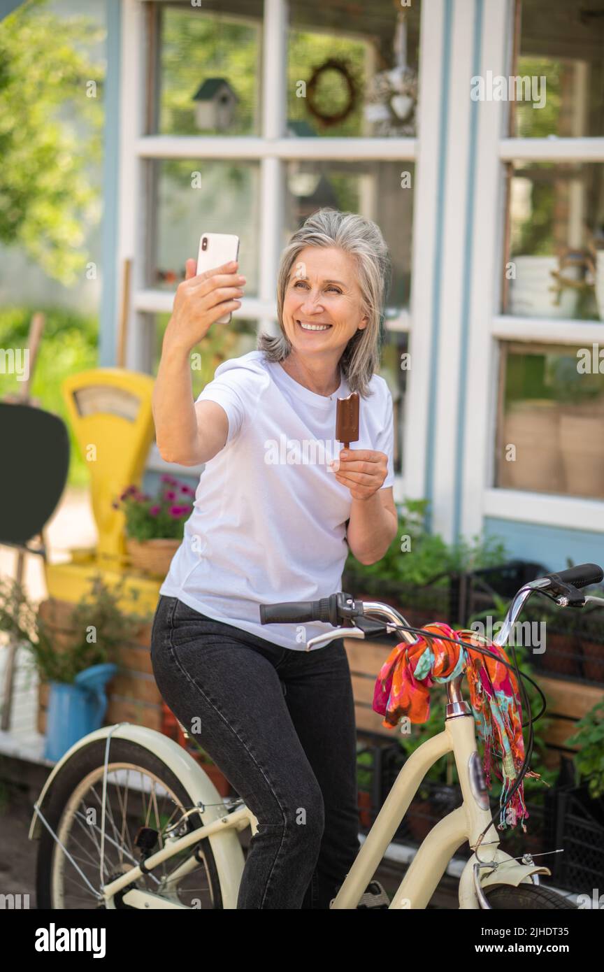 Cheerful woman on a bike eating ice-cream and looking happy Stock Photo ...