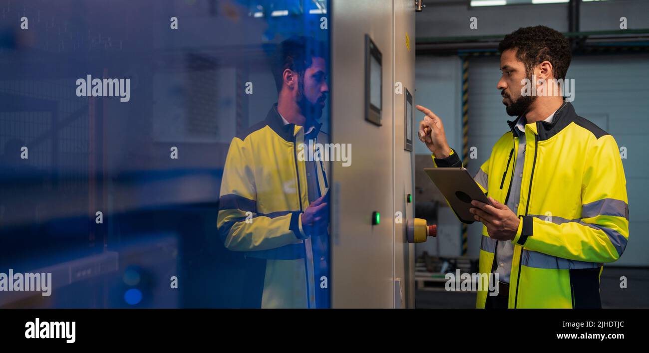 Young industrial worker operating cnc machine at metal machining ...