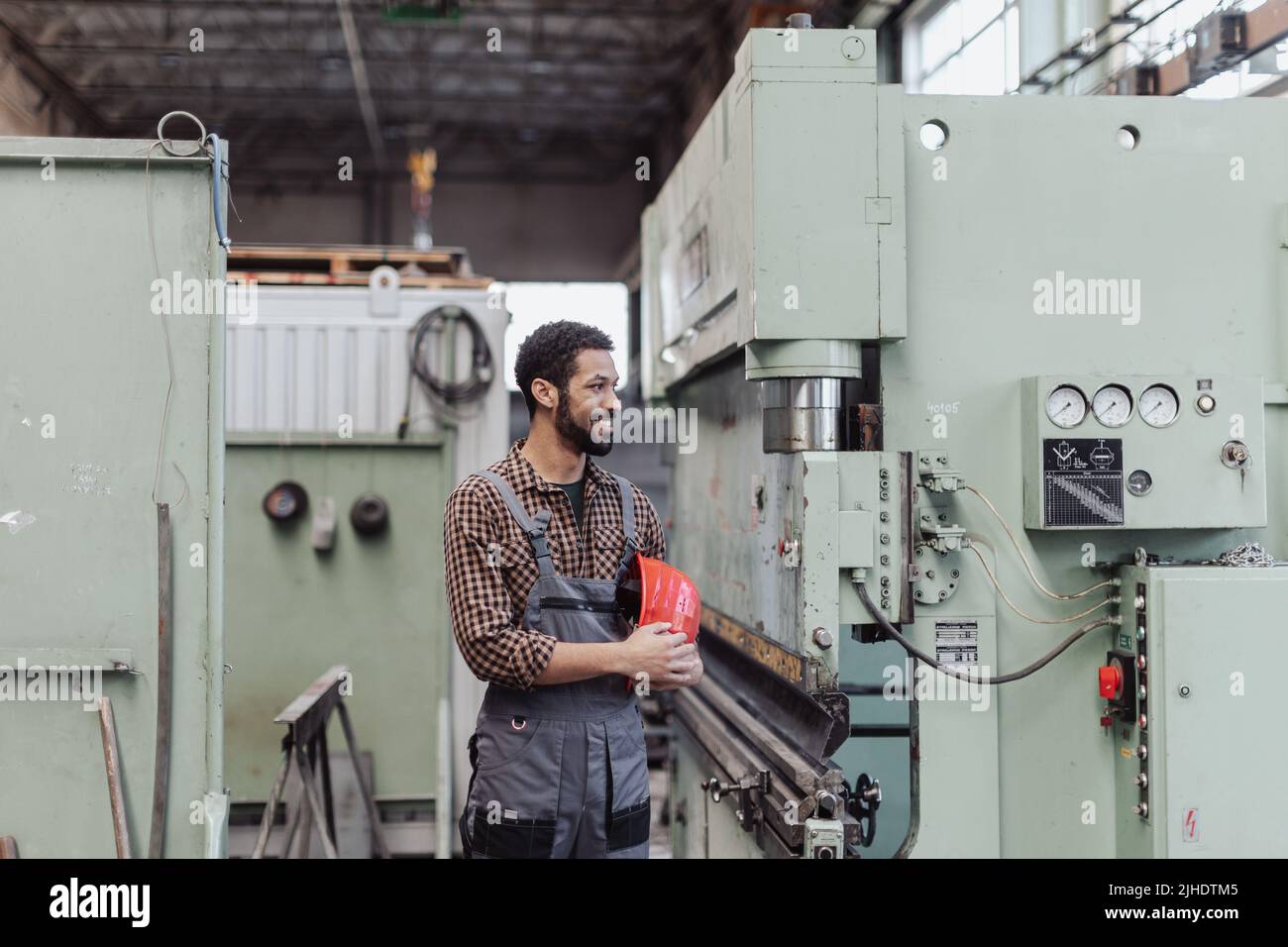 Heavy industry worker with safety headphones and hard hat in industrial ...