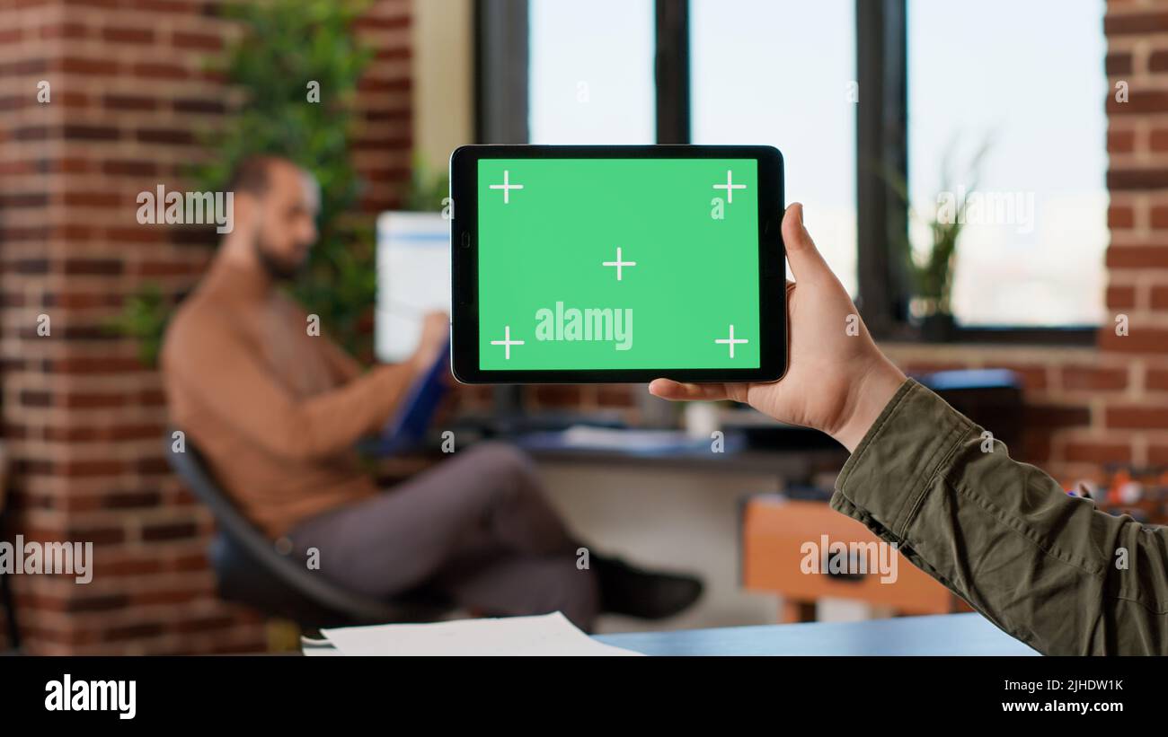 Male freelancer holding horizontal greenscreen on digital gadget, using ...