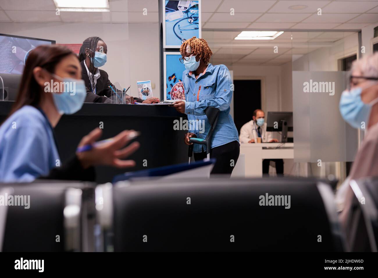 African american woman with crutches talking to receptionist in ...