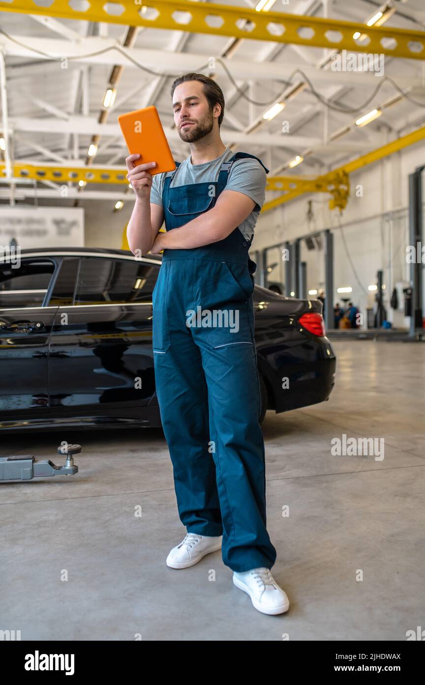 Man looking at tablet standing in car service Stock Photo - Alamy