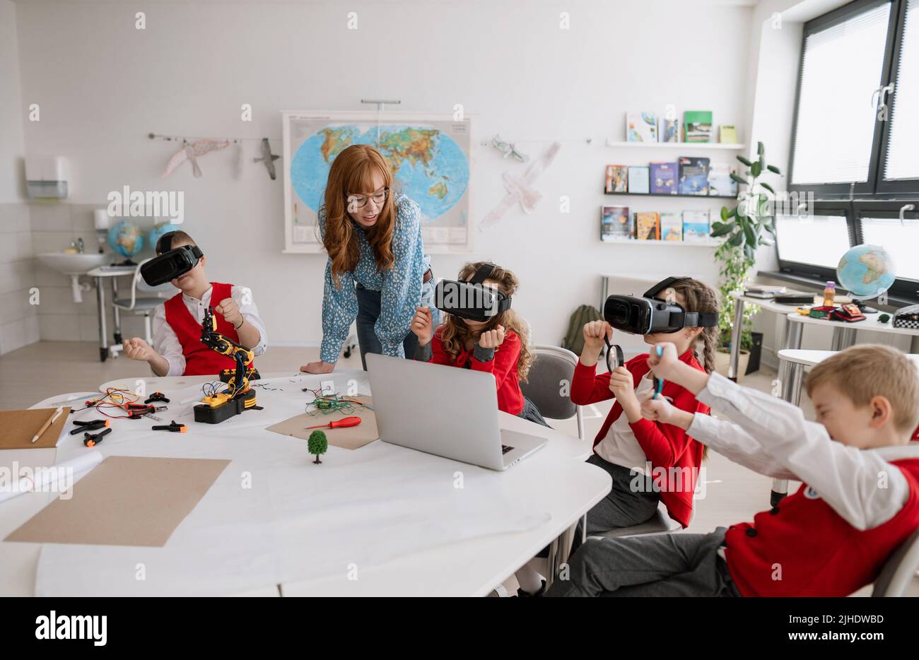 Happy schoolchildren wearing virtual reality goggles at school in ...