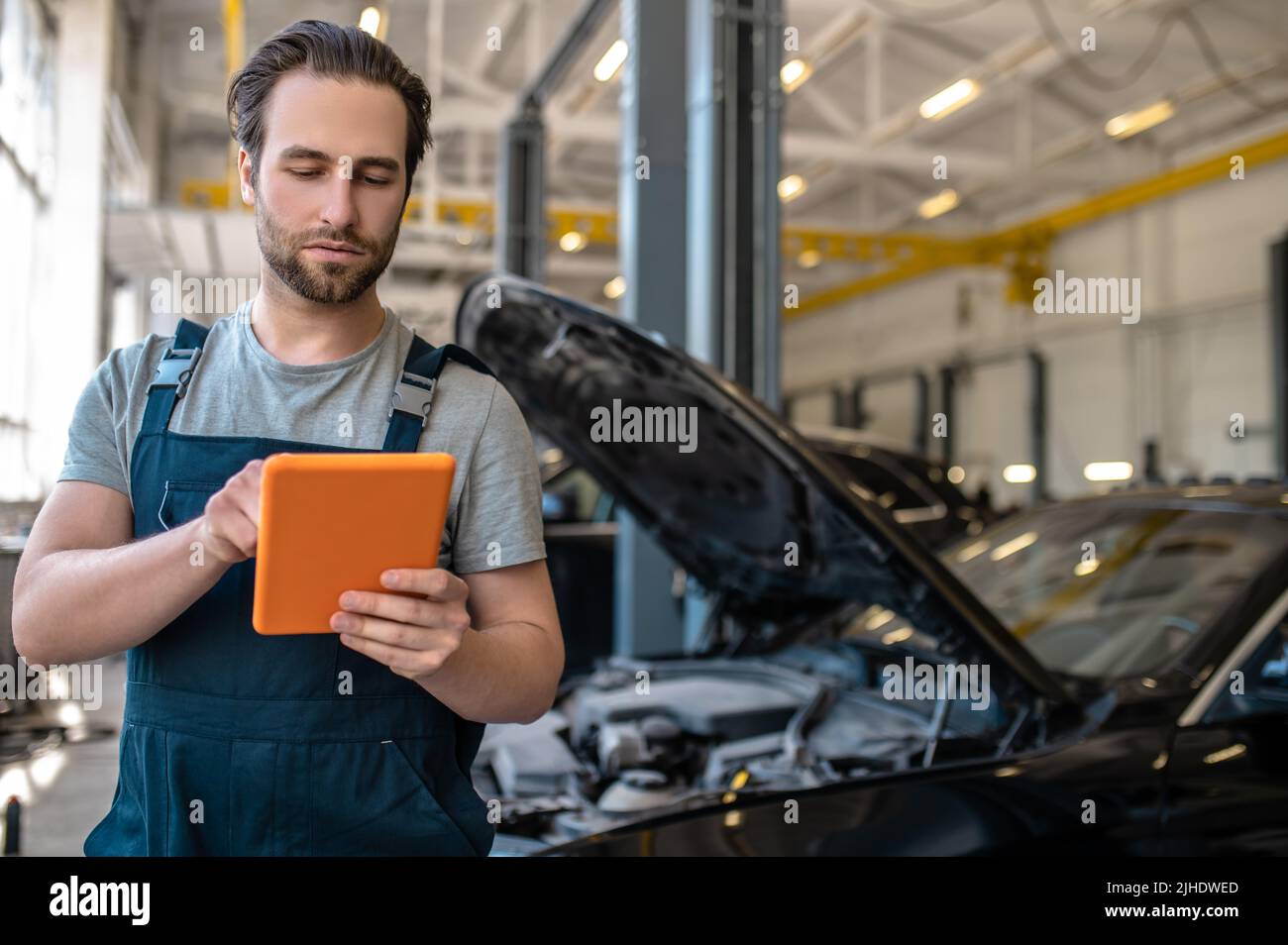 Concentrated man looking at tablet screen in service station Stock ...