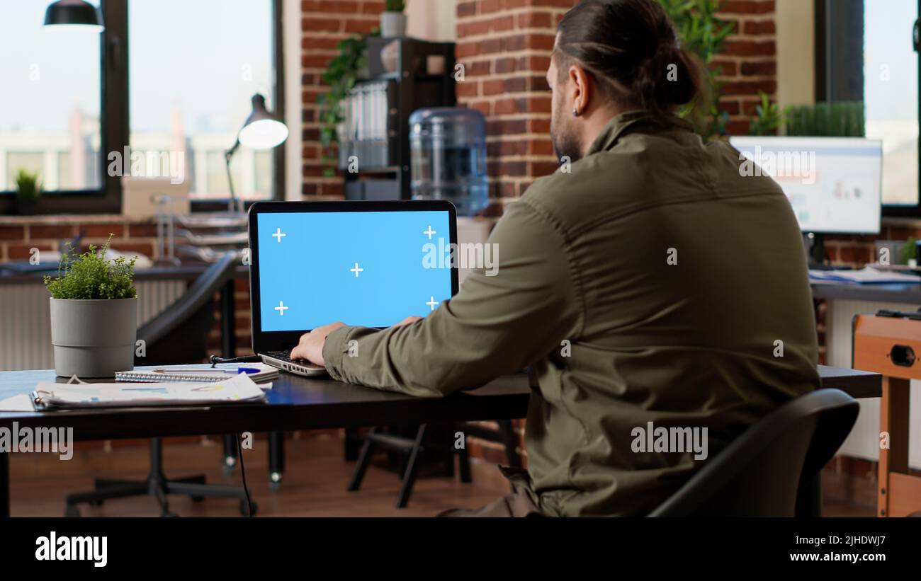 Office Worker Looking At Greenscreen Template On Laptop Working On