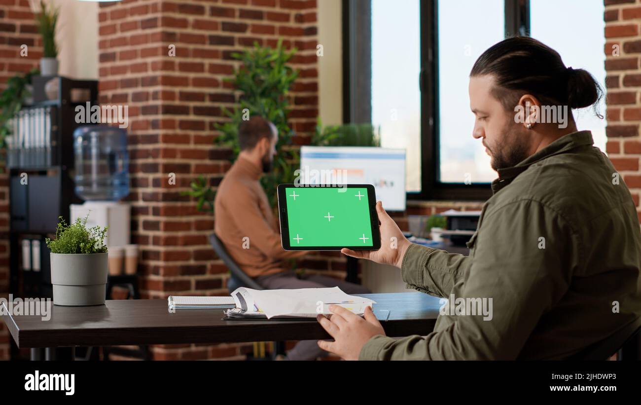 Male freelancer using horizontal greenscreen display on tablet, looking ...