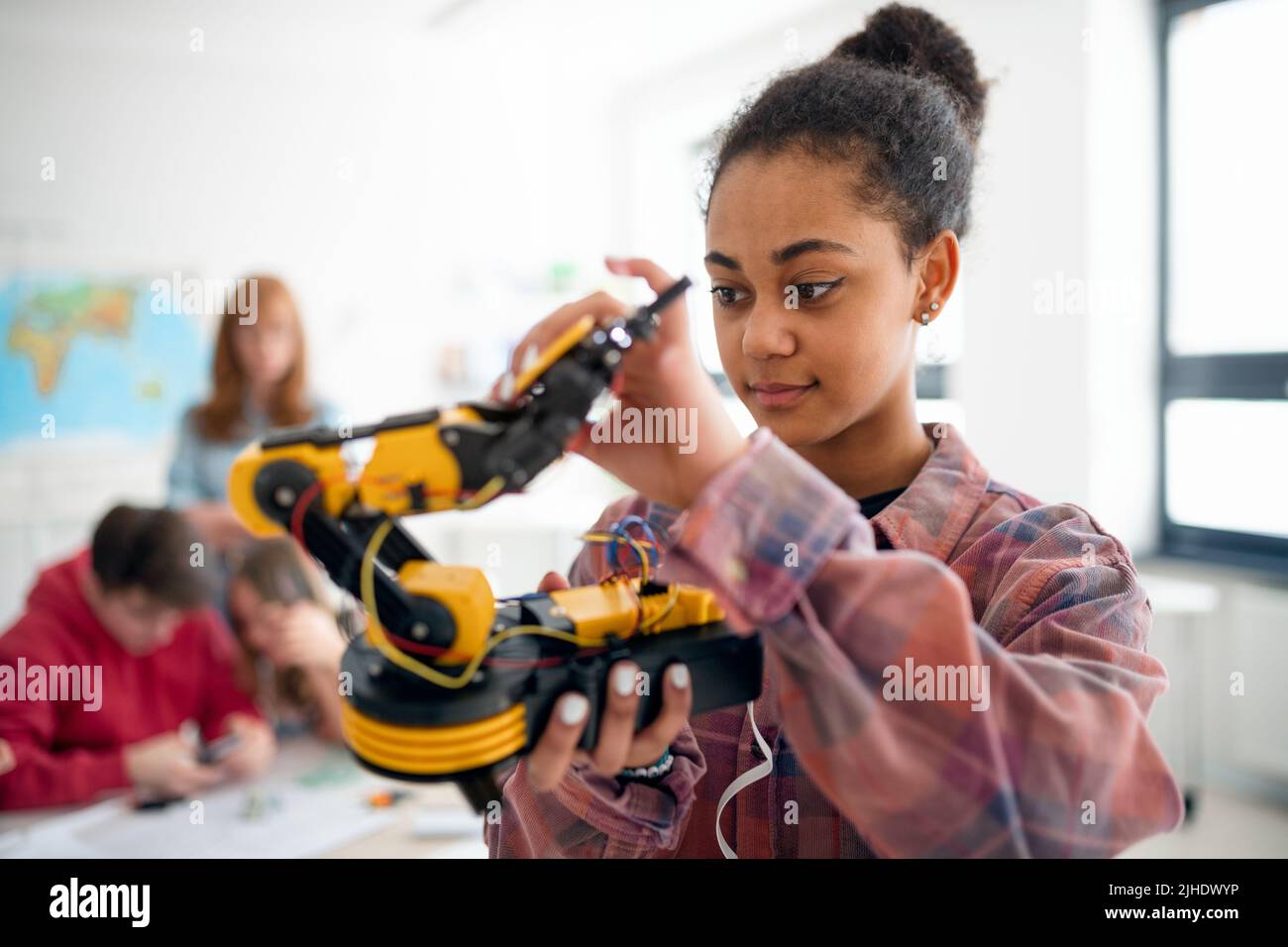 College student holding her robotic toy at robotics classroom at school ...