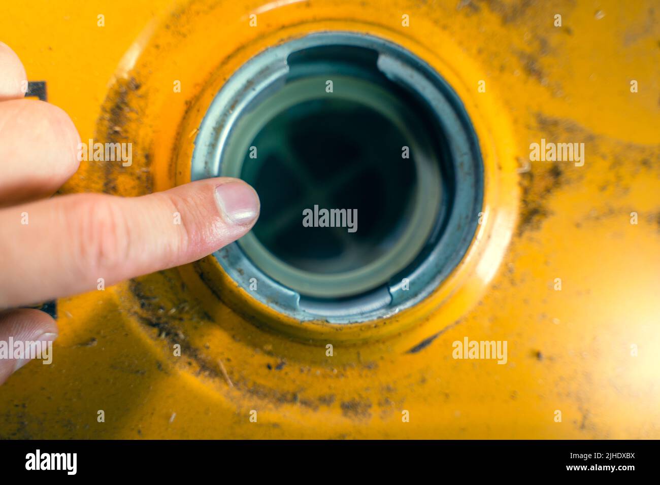 The finger points to the filler neck of the orange gas tank of the gas ...
