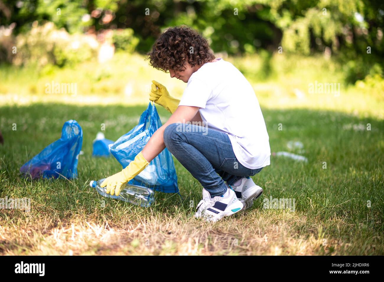 Young guy collecting and sorting garbage in the park Stock Photo - Alamy