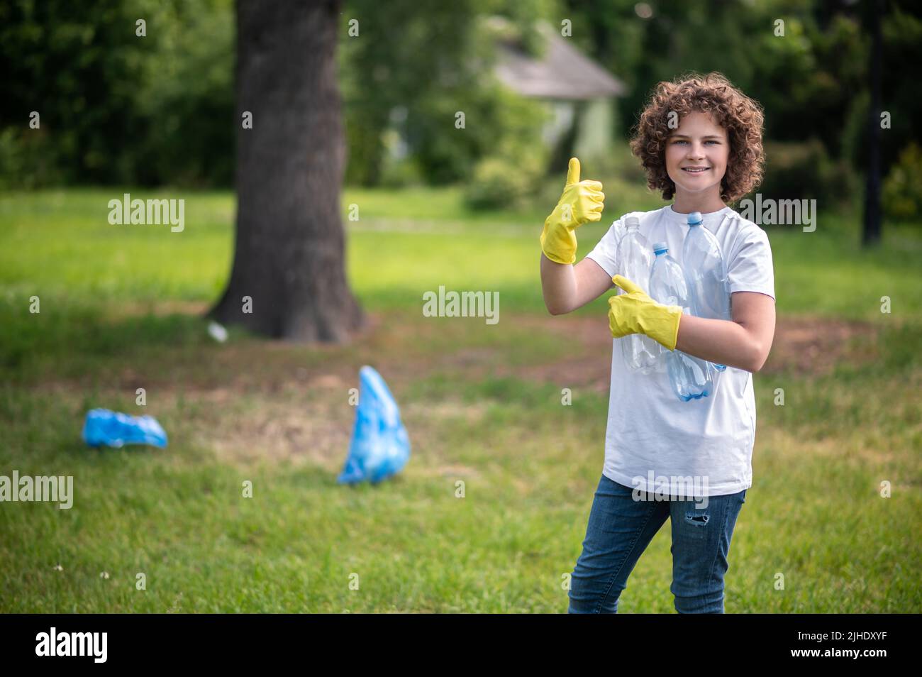 Smiling kid showing thumb up and looking contented Stock Photo - Alamy