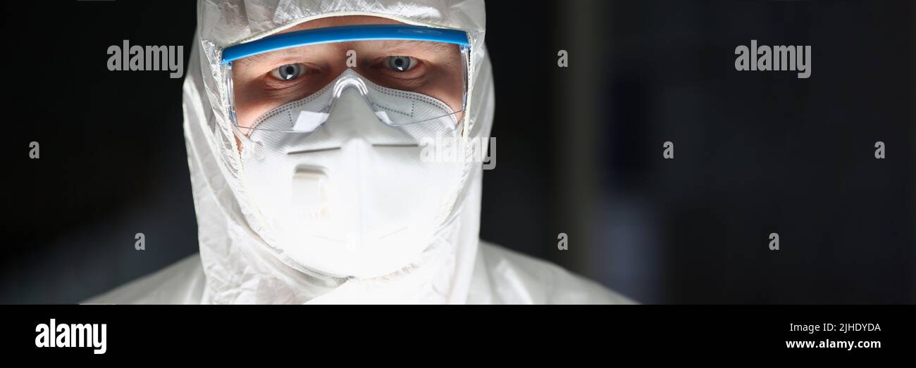 Male lab worker in protective respirator and white coverall, smart ...