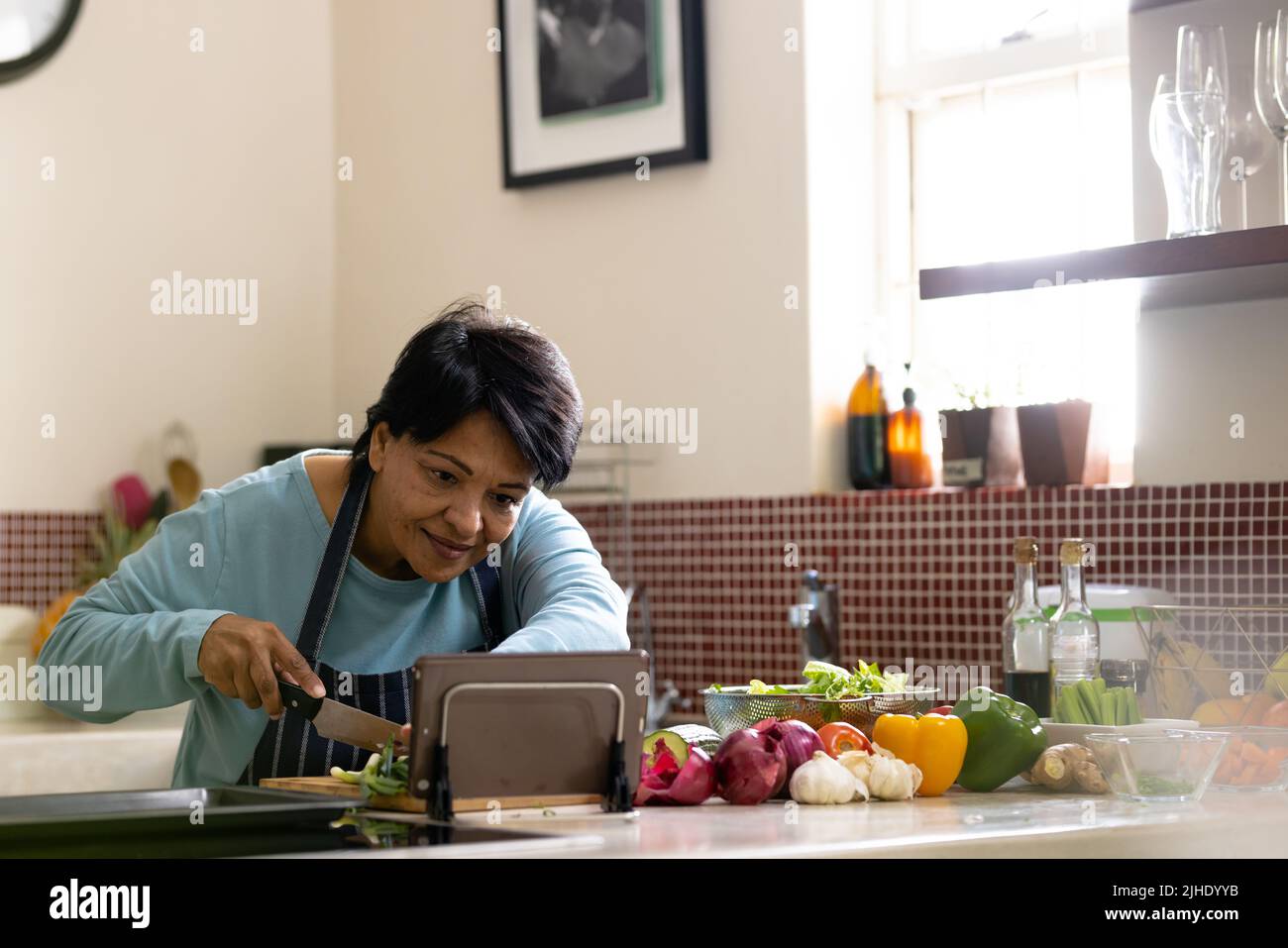 Biracial mature woman with short hair watching recipe over digital pc ...