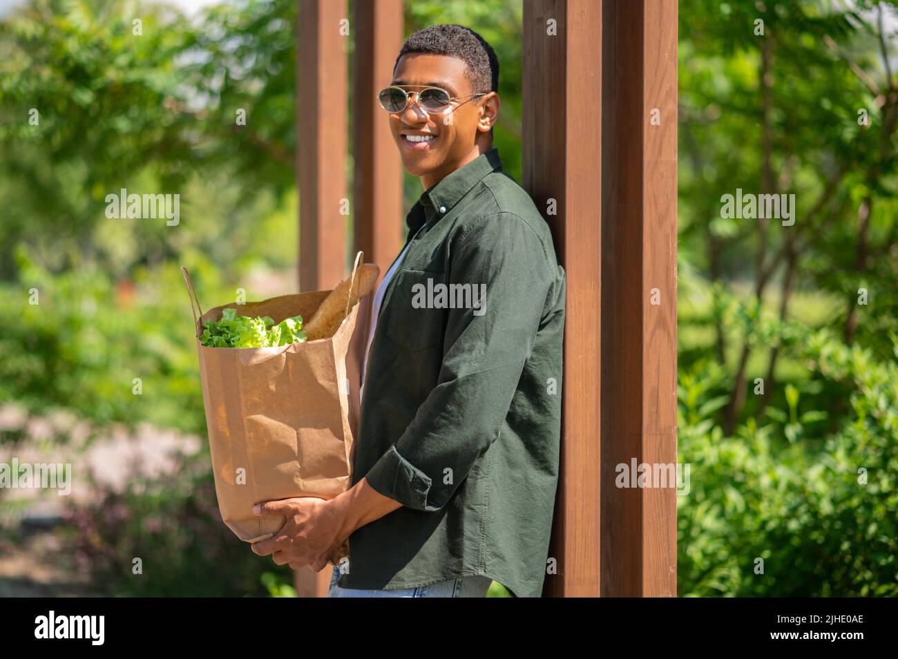 Man standing sideways to camera holding package Stock Photo - Alamy