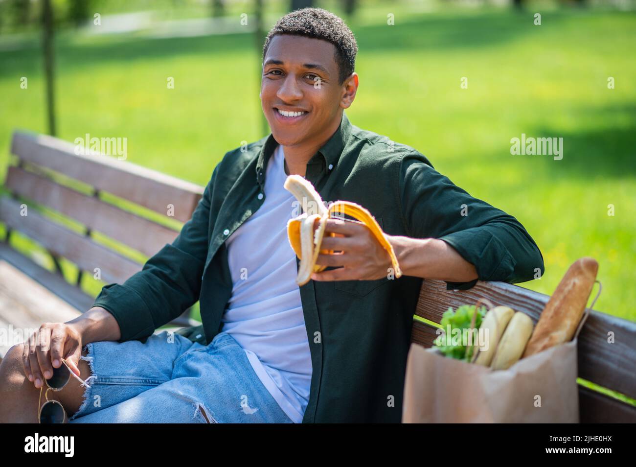 Guy smiling at camera sitting on bench Stock Photo - Alamy