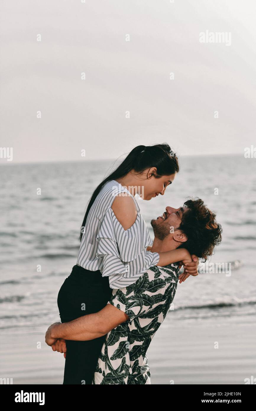 Young Happy Couple Holding Each Other On Beach Enjoying And Looking At