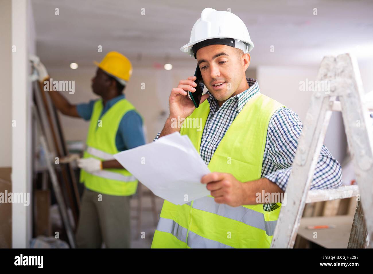 Portrait of foreman talking on phone about project documentation Stock ...