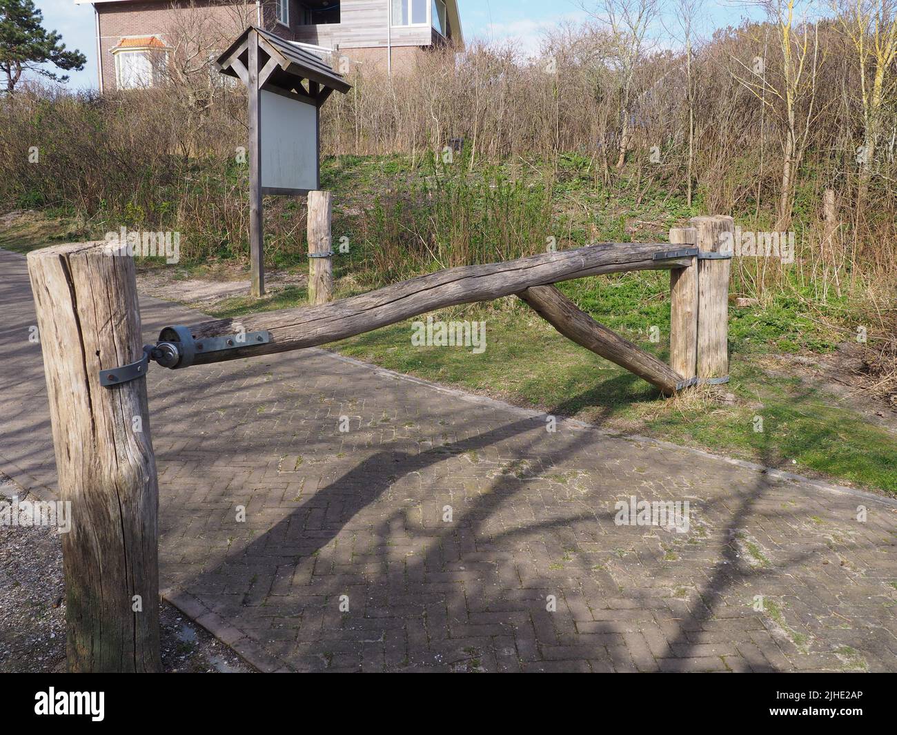 Wooden posts with gate tree trunks on a paved path Stock Photo - Alamy