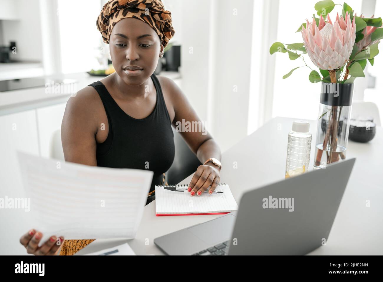 Black African woman working from home, going through paperwork and ...