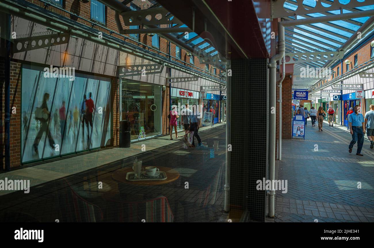 A shopping centre arcade, the reflections in a large shop window with ...