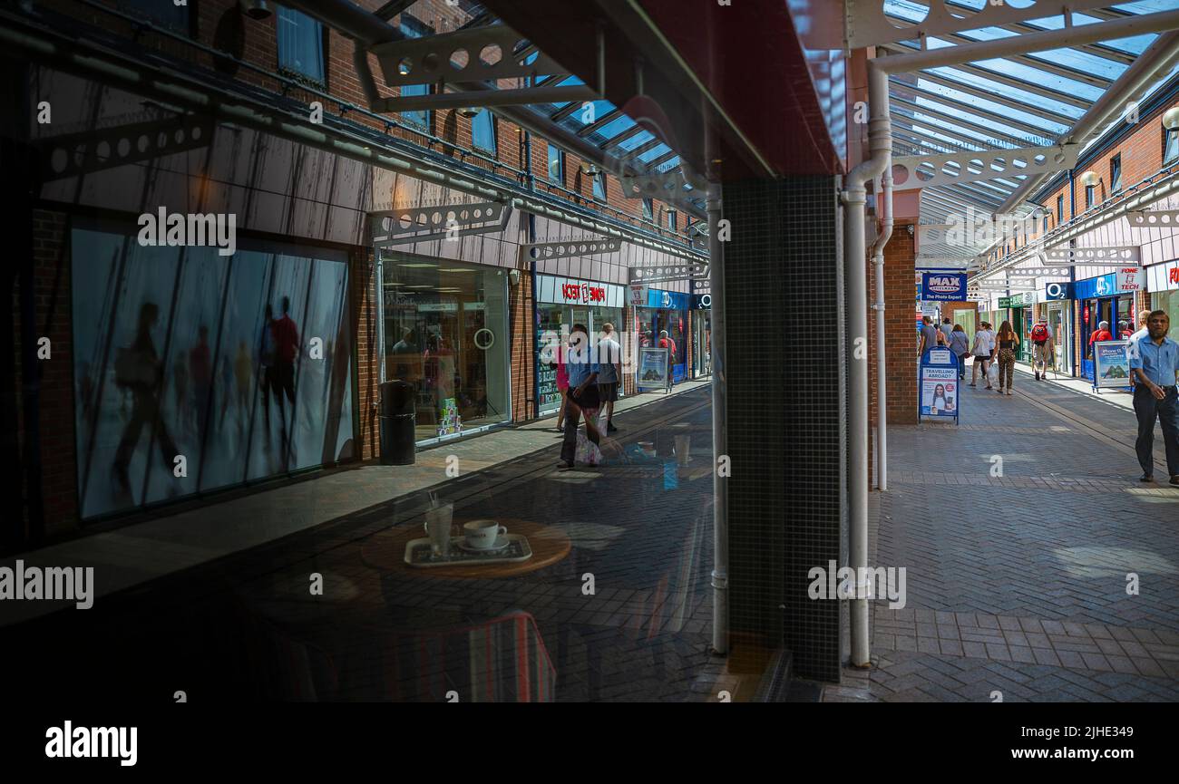 A shopping centre arcade, the reflections in a large shop window with ...
