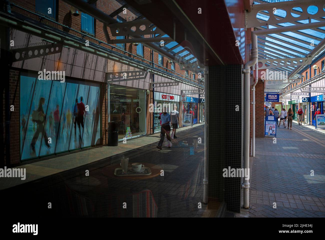 A shopping centre arcade, the reflections in a large shop window with ...