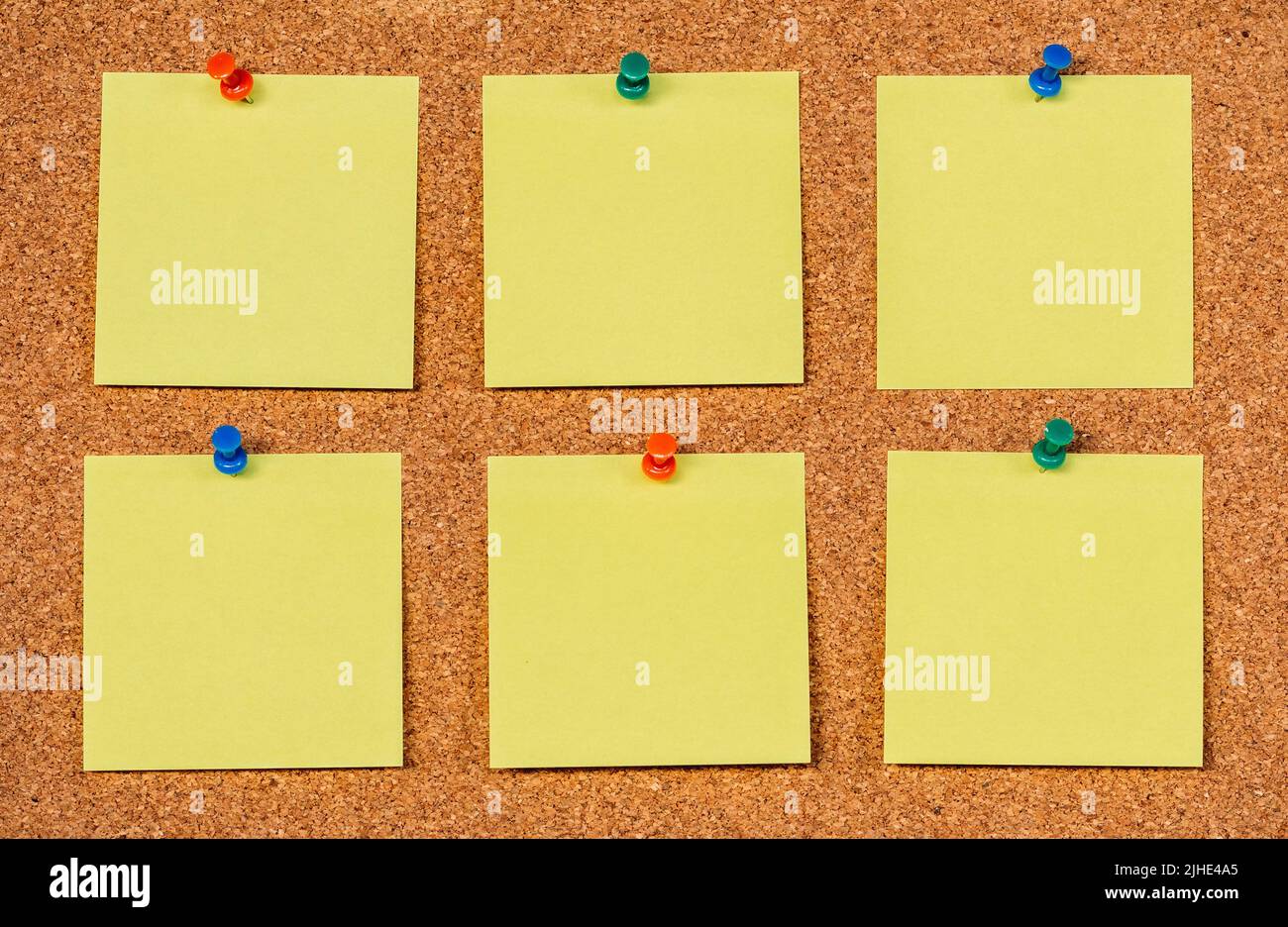 Six empty yellow sticky notes on a cork board with drawing pins, copy ...