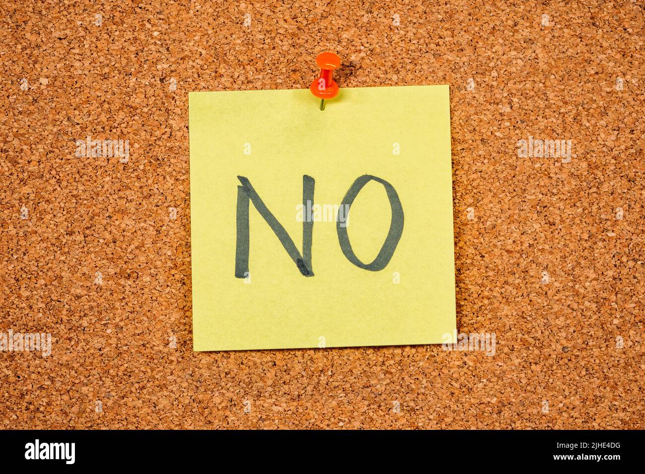 Yellow sticky note on a cork board with drawing pin with the word No ...