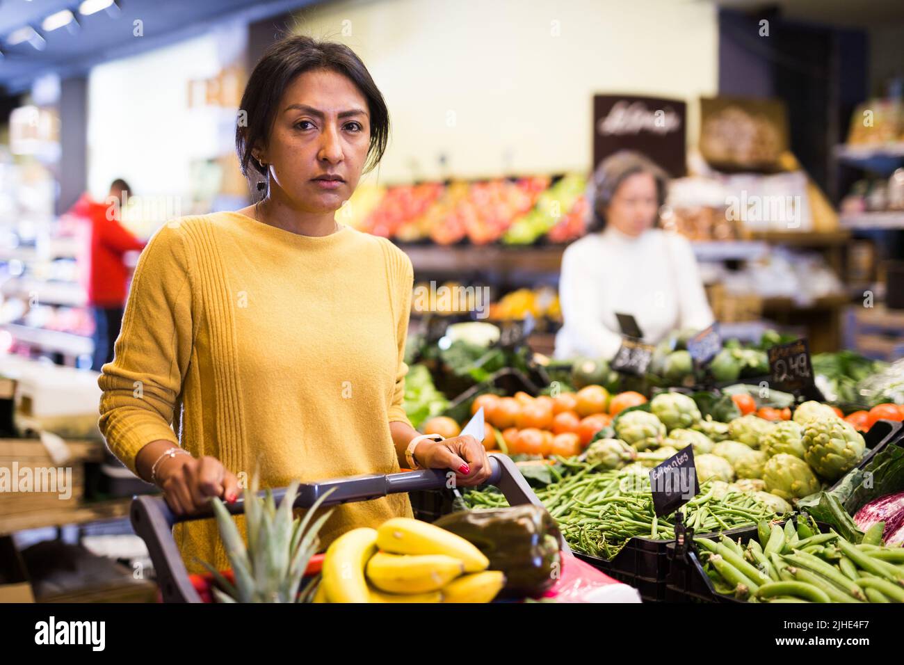 Hispanic woman walking with shopping trolley in grocery shop Stock ...