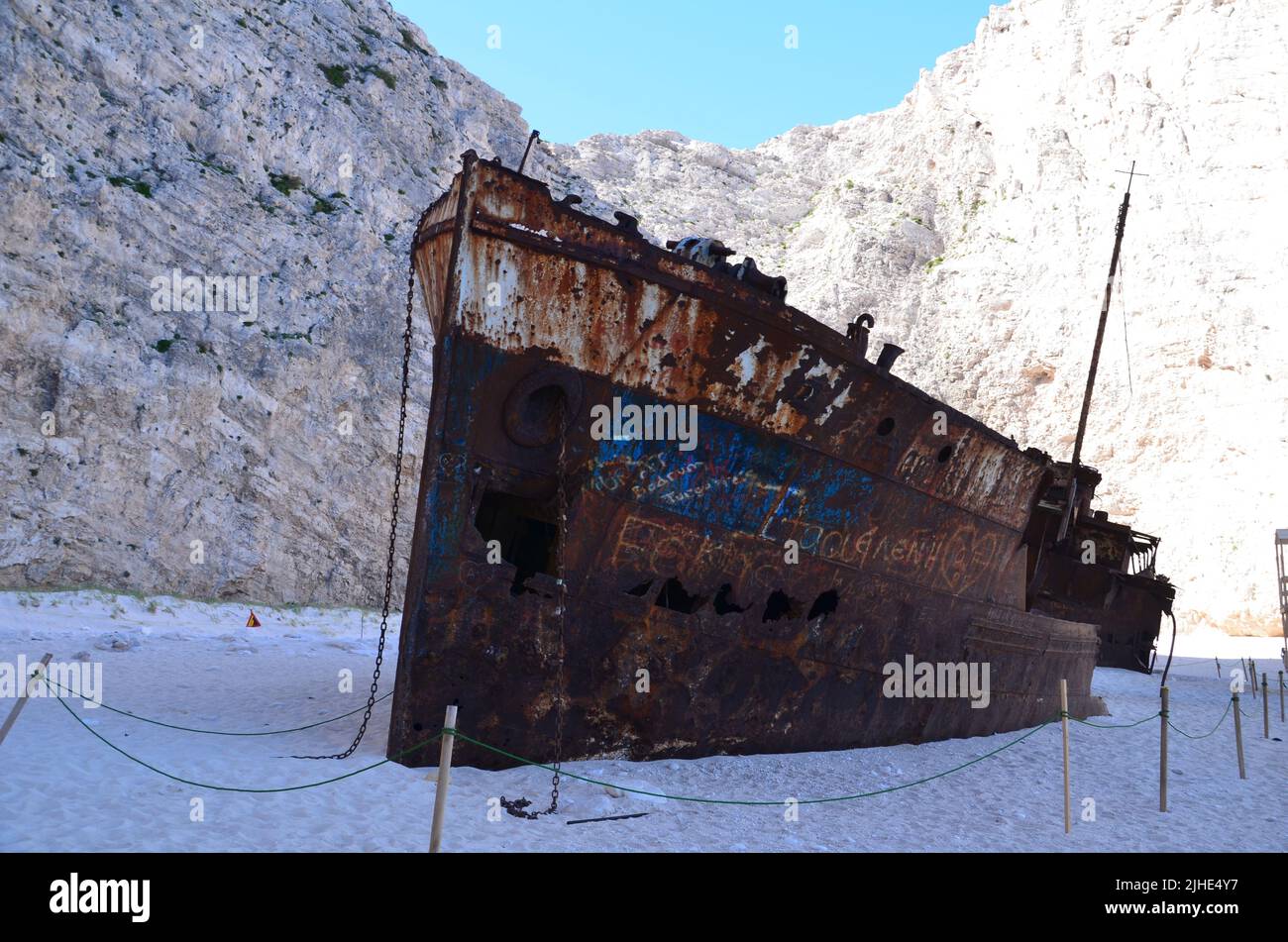 rusty shipwreck with high rocks in background at Naviago beach ...