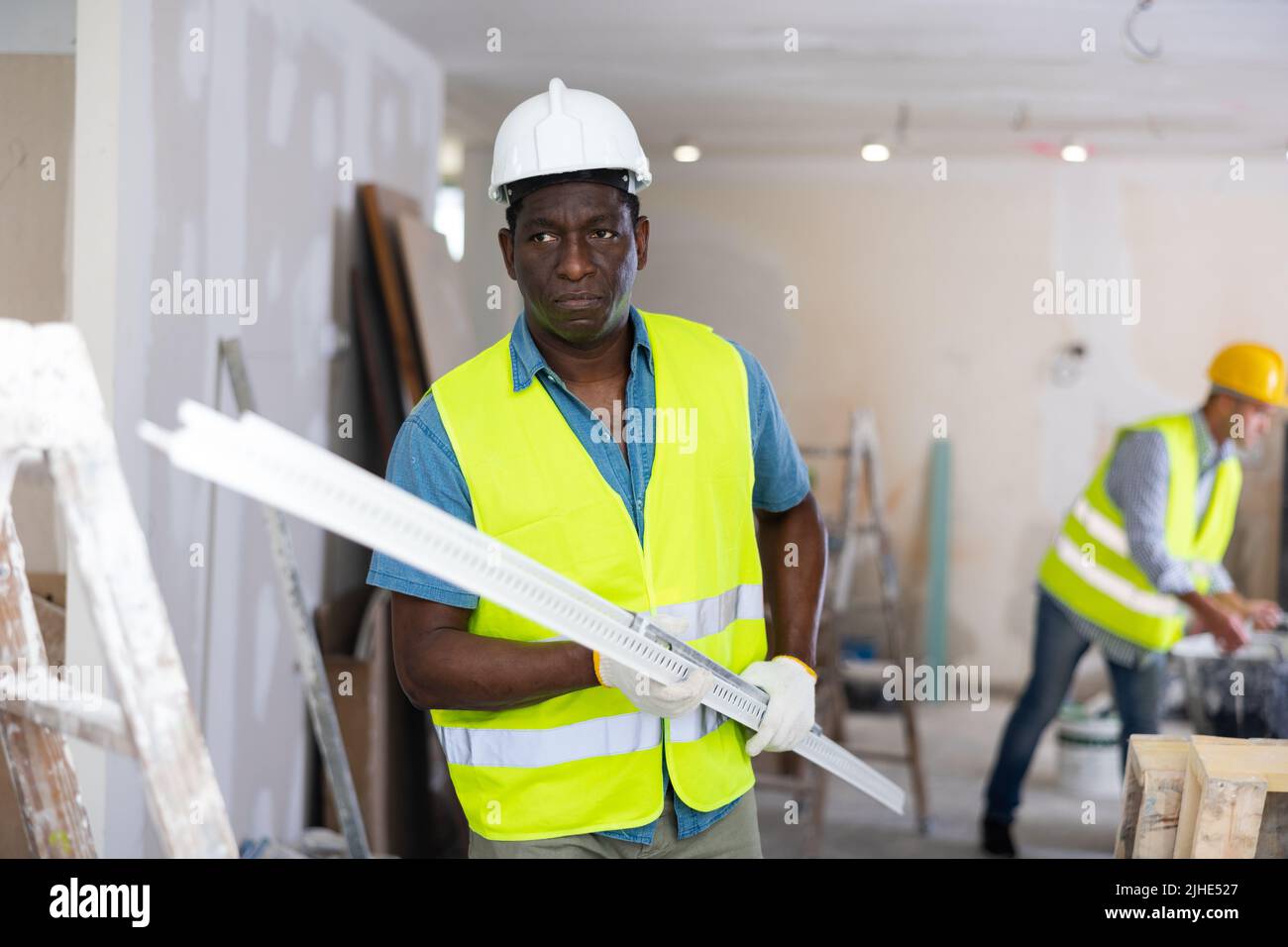 African-american man builder carrying metallic profile while working in ...