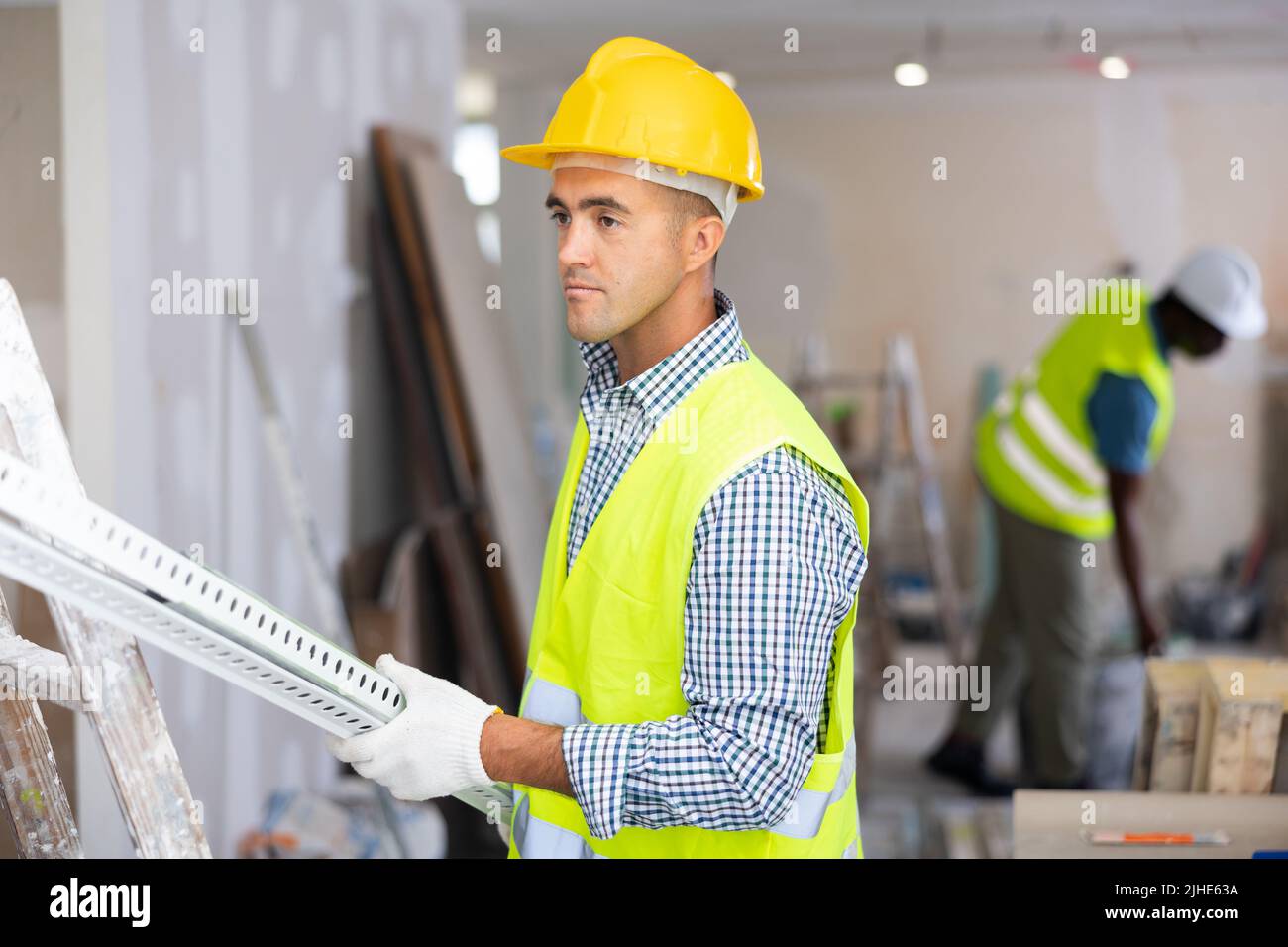 Man builder carrying metallic profile while working in construction ...