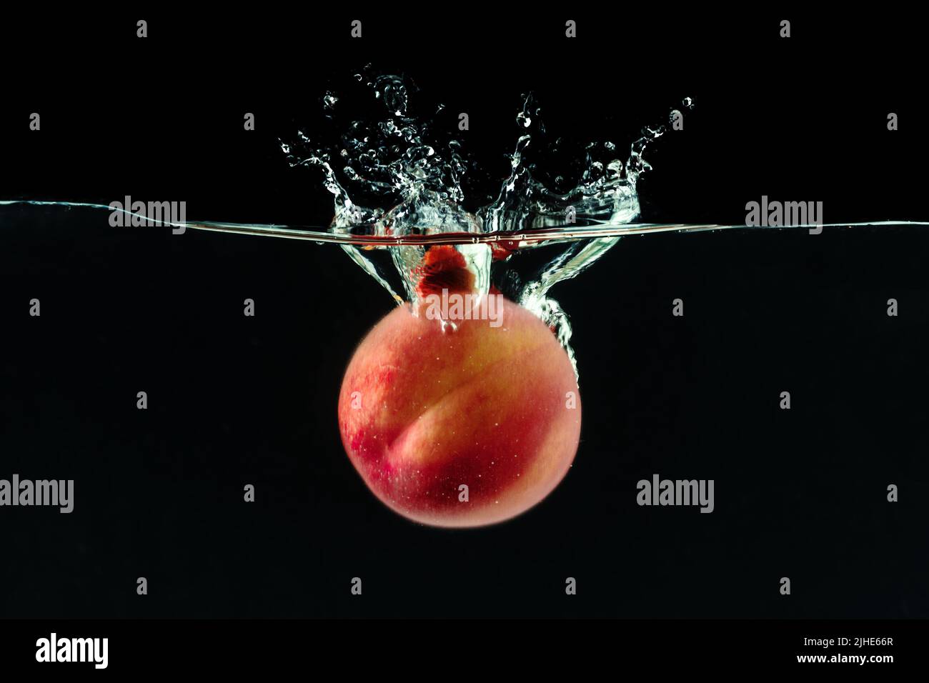 Peach dropped into water with bubbles Stock Photo - Alamy