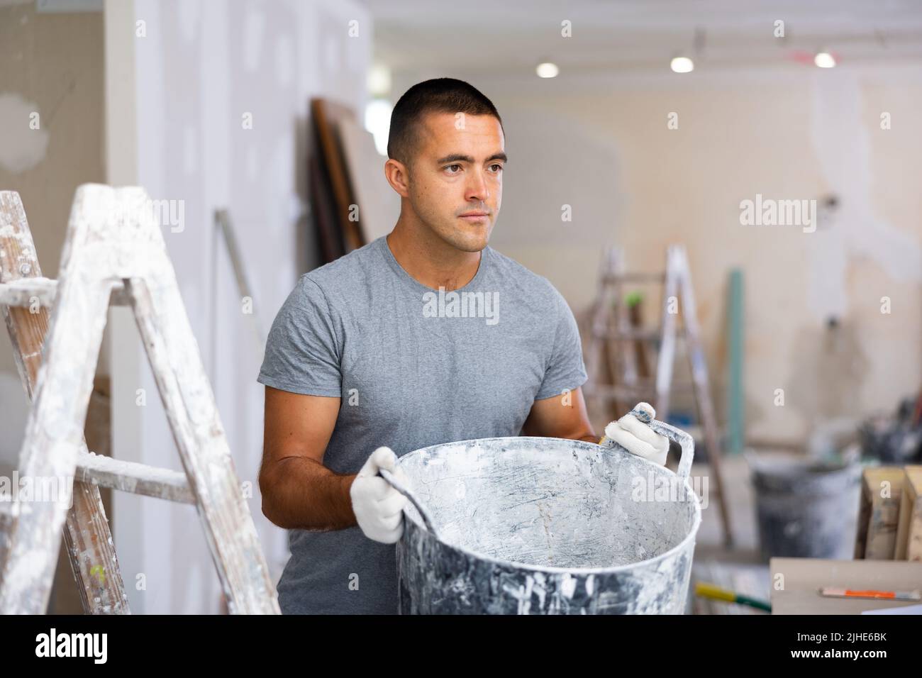 Man carrying bucket in construction site Stock Photo - Alamy