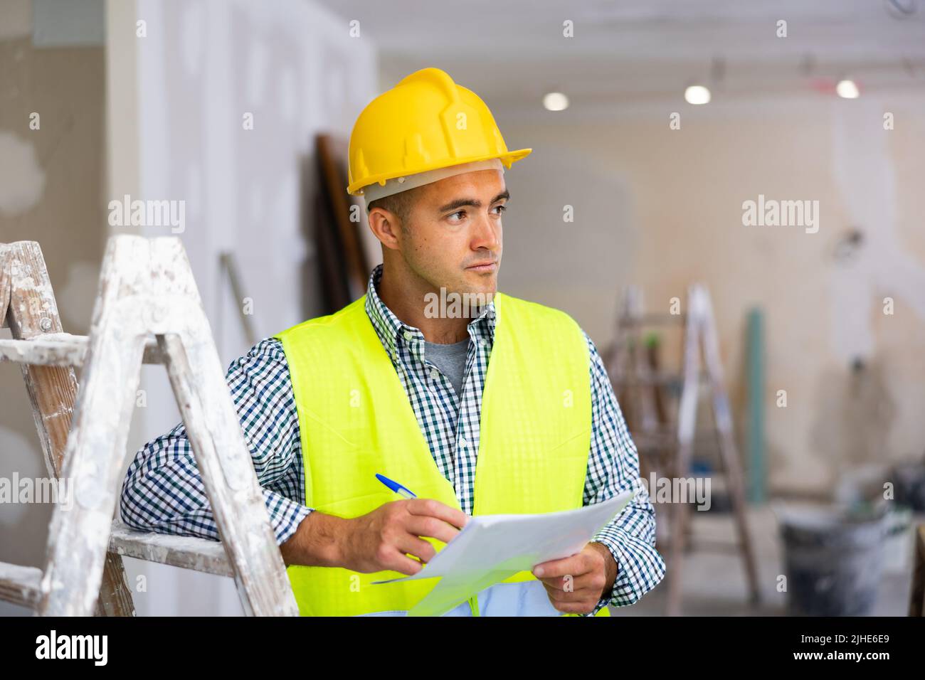 Young foreman checks the completed construction work and signs the ...